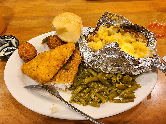 Fried catfish golden as an Alabama sunset, served with green beans cooked low and slow, and a baked potato wrapped like a precious gift.