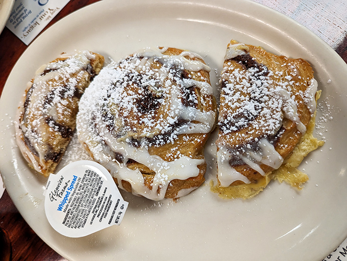 Cinnamon rolls dusted with powdered sugar and drizzled with icing—proof that sometimes dessert masquerading as breakfast is exactly what you need.