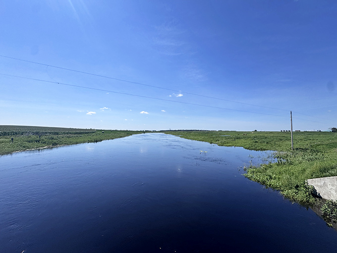 This serene creek reflects perfect blue skies, creating a mirror-like surface that doubles the beauty of North Dakota's expansive horizon.