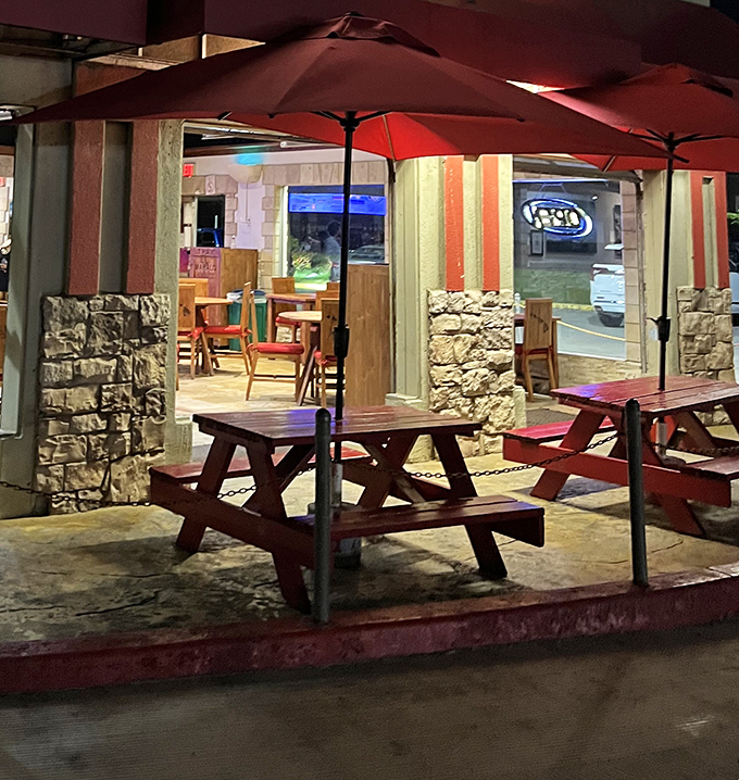 Those red picnic tables under umbrellas aren't just seating – they're front-row tickets to the perfect casual dining experience.