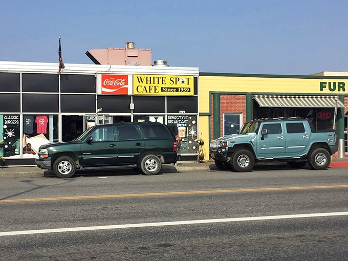 Humble storefront, extraordinary food inside. Cars parked outside White Spot Cafe know what many travelers miss&mdash;authentic Alaskan comfort food awaits within.