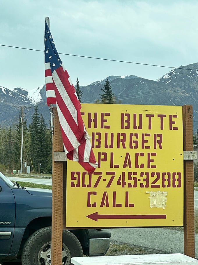 Follow the flag to find the flavor! Against a backdrop of majestic mountains, this sign points the way to burger nirvana.