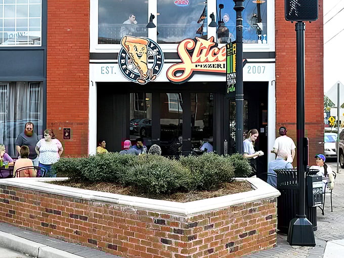 The inviting storefront of Slices Pizzeria in Griffin beckons with its cheerful yellow sign &ndash; like a beacon of cheesy goodness on a brick-lined street.