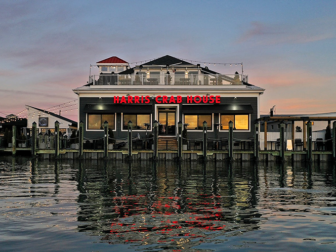 Twilight transforms this dockside crab house into a postcard scene. Those red letters promise seafood magic inside.