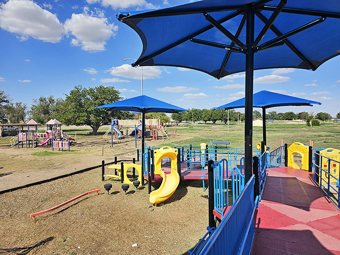 Chaparral Park offers a colorful playground oasis where the bright blue umbrellas mirror the vast New Mexico sky above.