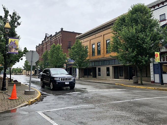 Rain-slicked streets reflect Fostoria's timeless brick facades, creating a Norman Rockwell painting where modern SUVs seem almost anachronistic against the 19th-century backdrop.