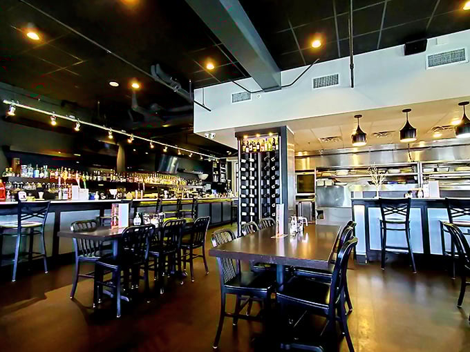 Inside, modern elegance meets cozy comfort with dark ceilings, warm wood tables, and a bar that practically whispers, "Order something fun."