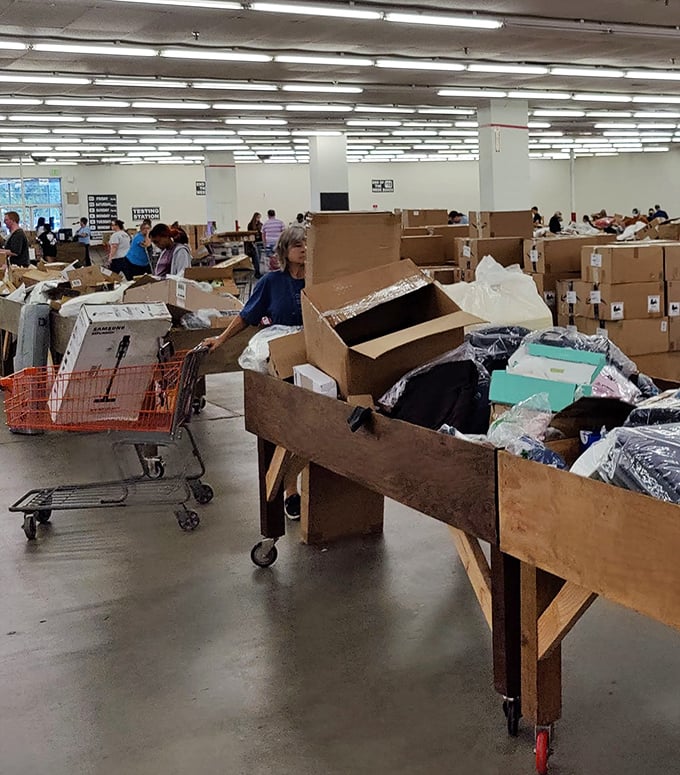 Organized chaos at its finest! Shoppers navigate wooden bins filled with potential finds, like archaeologists on a dig where X marks the bargain.