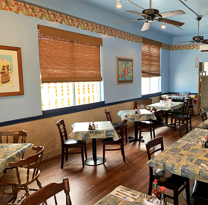 Simple wooden tables with floral tablecloths create that "grandma's dining room" vibe where comfort trumps pretension and breakfast reigns supreme.