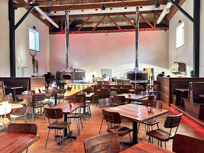 High ceilings, exposed beams, and twin wood-fired ovens create a dining space where rustic Wyoming meets Italian craftsmanship.