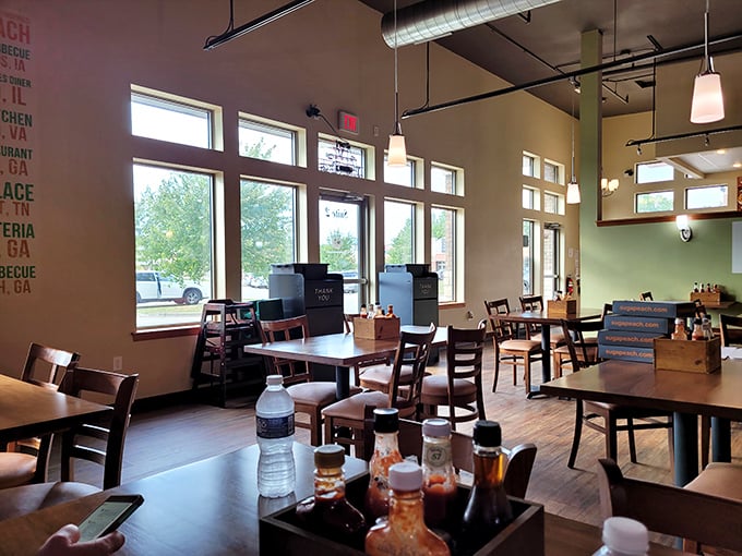 Sunlight floods the dining room, where wooden tables await hungry patrons. The green accent wall adds warmth to a space where comfort food reigns supreme.