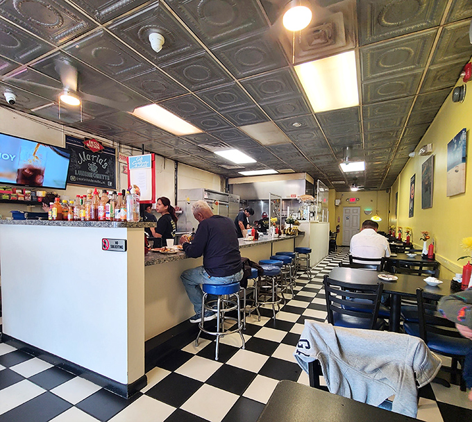 Classic diner counter seating where regulars become family and first-timers become regulars. That black and white checkered floor has witnessed countless breakfast epiphanies.