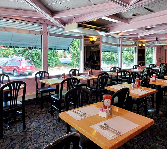 Pink ceiling trim and wooden tables create that classic diner atmosphere where conversations flow as freely as the coffee.