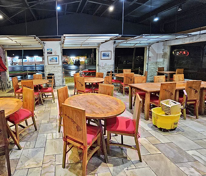 Rustic wooden tables with bright red cushions create that perfect "come as you are" vibe where island time meets mealtime.