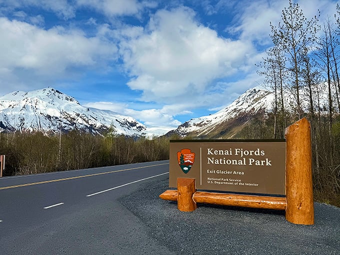 The park entrance sign stands against a backdrop of snow-capped peaks, nature's version of the world's most impressive welcome mat.