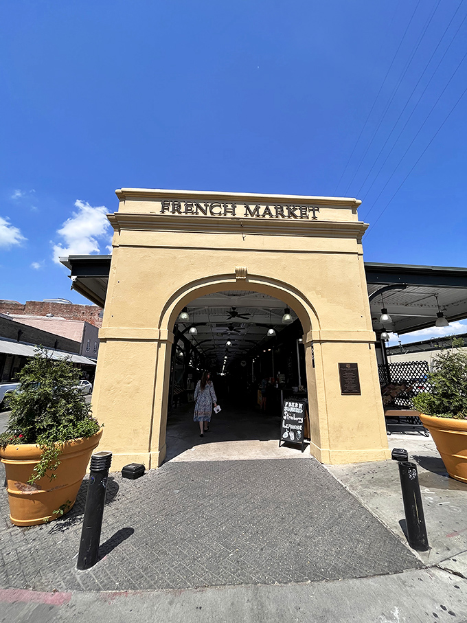Sunlight streams through the French Market's entrance, illuminating a path that generations of bargain hunters have traveled in search of the perfect souvenir.