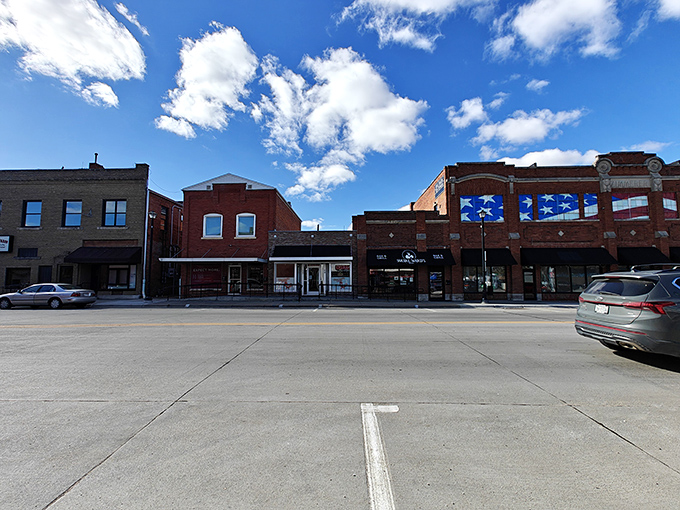 The red-brick anchor building commands attention at the corner, while awnings in forest green, crimson, and navy create a welcoming rhythm down the block.