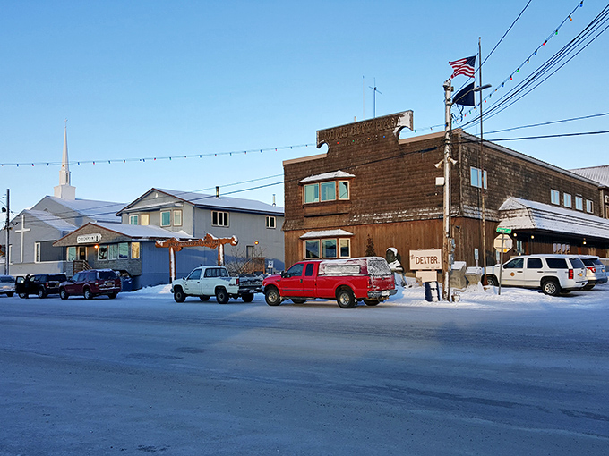 Winter transforms Nome's Front Street into a snow-dusted postcard where pickup trucks replace tauntauns as the preferred transport.