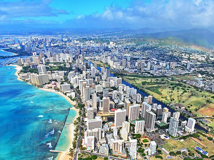 Downtown Aiea sparkles like jewelry against the blue Pacific, with iconic Waikiki Beach curving along the shoreline.