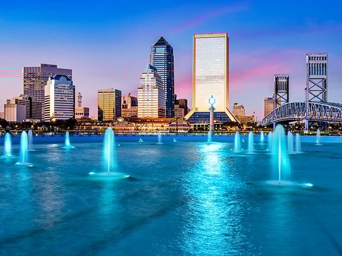 Jacksonville's skyline glows at twilight, with blue fountains dancing in the foreground beneath a cotton candy sky.