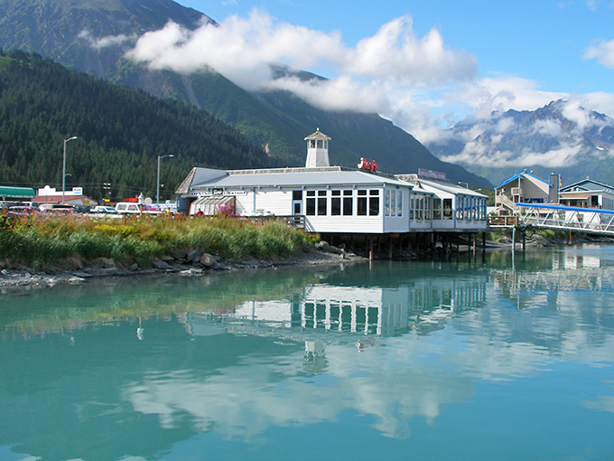 Seward&rsquo;s marina, where calm turquoise waters reflect dockside buildings and the surrounding mountains.