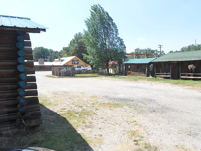 Historic log cabins line the dusty main street of this charming Wyoming small town on a sunny summer day.