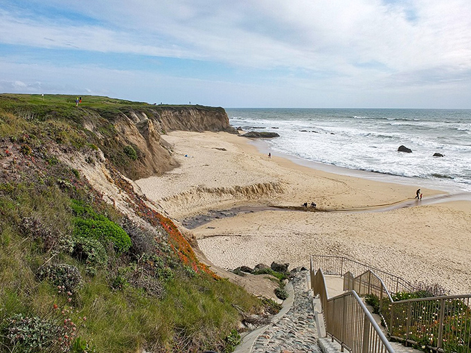 Coastal stairs lead down to sandy shores where Pacific waves write daily love letters.
