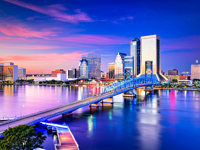 Jacksonville's skyline glows with cotton candy skies as the iconic blue bridge spans the St. Johns River at sunset.
