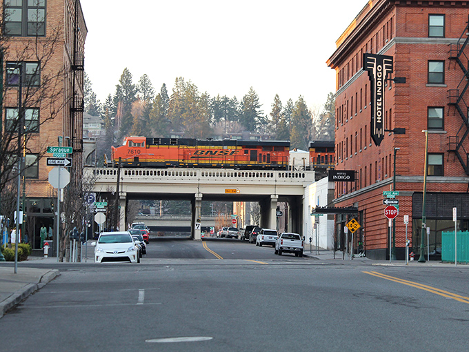 Trains rumble through downtown Spokane beneath historic brick buildings, where affordable living meets unexpected urban charm.