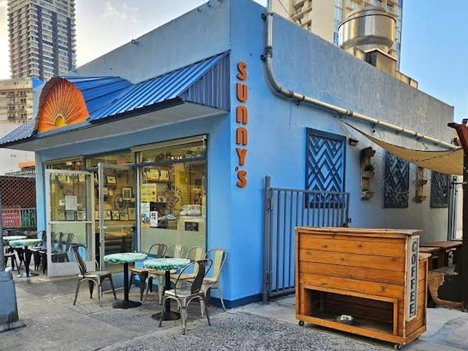 Sunny's Local Grind brings the cheerful vibes with its vibrant blue exterior. The outdoor seating area practically whispers, "Coffee with a view."