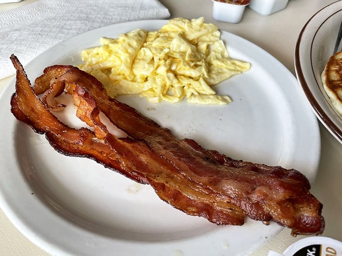 Bacon cooked to that perfect sweet spot between chewy and crisp, alongside fluffy scrambled eggs that practically float off the plate.