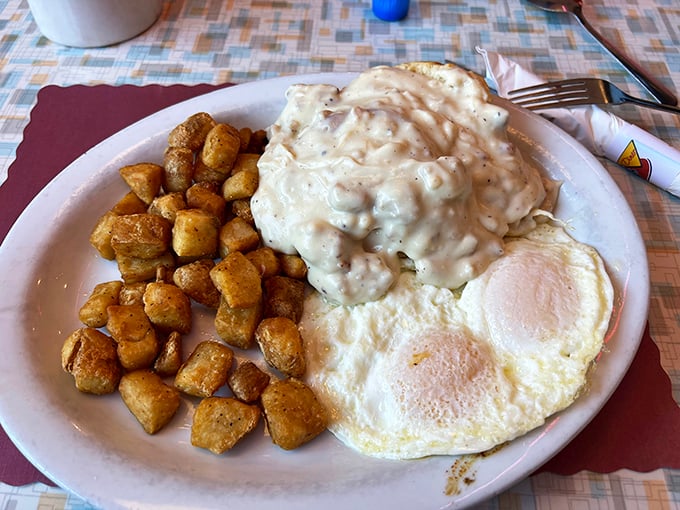 Biscuits smothered in creamy sausage gravy alongside golden potatoes and sunny-side-up eggs &ndash; a breakfast plate that demands to be photographed before it's devoured.