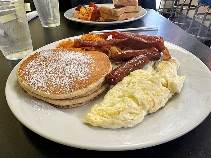 The breakfast trinity: golden pancakes, fluffy scrambled eggs, and sausage links that snap with each bite. A plate that says "good morning" better than words ever could.