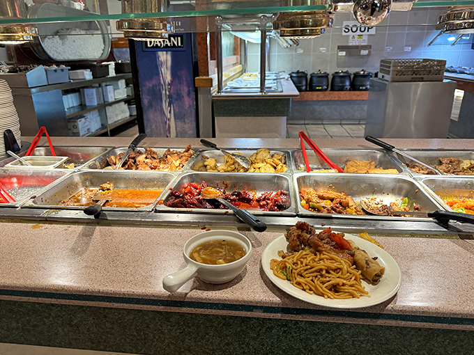 A plate of noodles and savory delights awaits its destiny, while the buffet's bounty stretches into the distance like a delicious horizon.