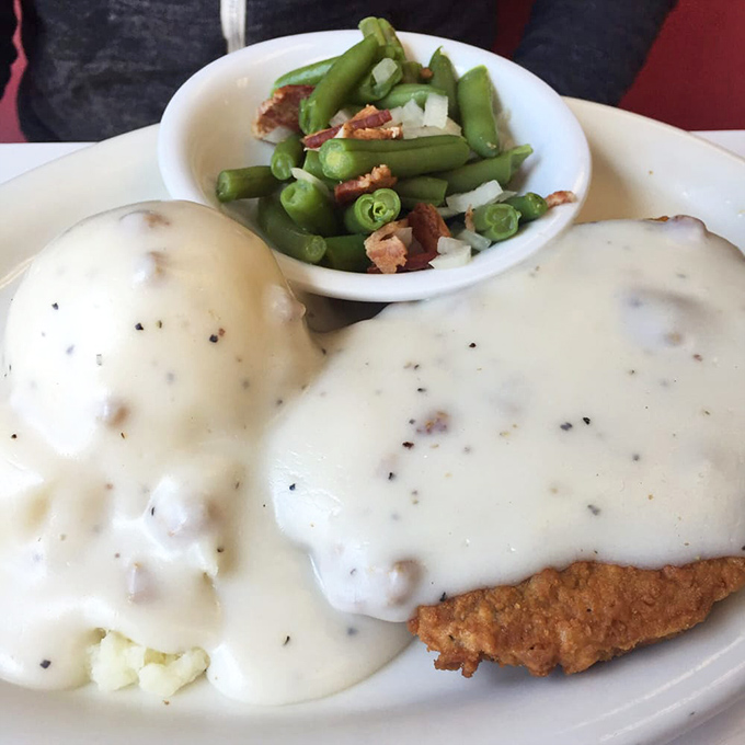 Behold the legendary chicken fried steak in all its glory – golden-crisp exterior, pepper-flecked gravy cascading like a savory waterfall, and green beans that actually taste fresh.