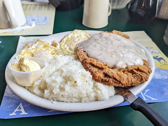 Behold the star of our show: chicken fried steak with gravy cascading over its golden shores, accompanied by grits that look like they've been whispering secrets to Southern grandmothers.