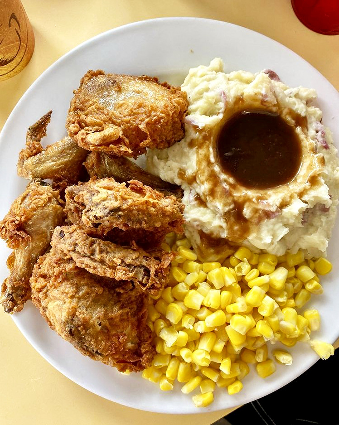 Golden-fried chicken that crackles with each bite, nestled beside mashed potatoes with a gravy lake worthy of diving in.