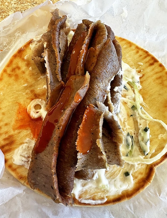 Behold the star of the show &ndash; thinly sliced gyro meat nestled on a warm pita with creamy tzatziki. This isn't just food; it's edible poetry.