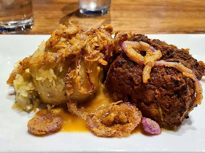 The legendary meatloaf arrives like a celebrity, surrounded by crispy onion rings and mashed potatoes. Comfort food that went to finishing school.