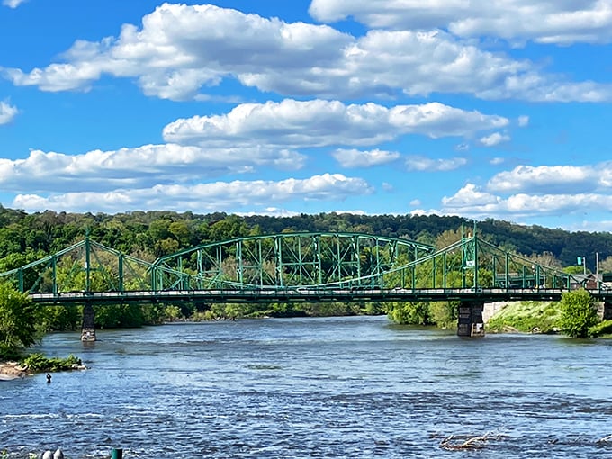 The iconic green Northampton Street Bridge spans the Delaware River like a steel sentinel, connecting New Jersey to Pennsylvania under skies that seem impossibly blue.