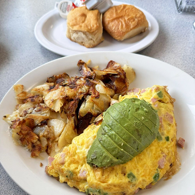 Behold the perfect omelet—fluffy exterior, generous fillings, and that half avocado perched on top like a crown jewel of California breakfast royalty.