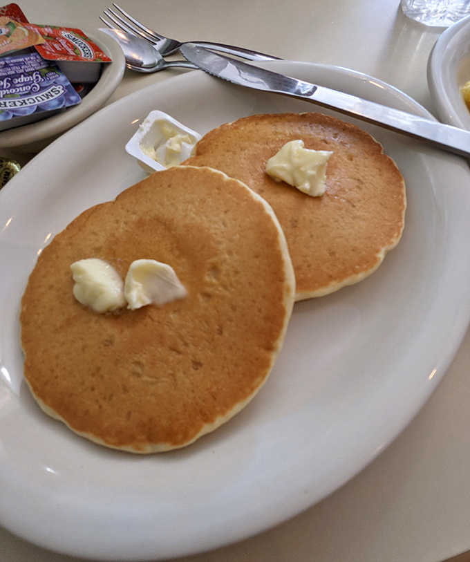 Golden pancakes wearing little hats of butter, patiently waiting for their syrup shower. Breakfast doesn't get more straightforward than this.