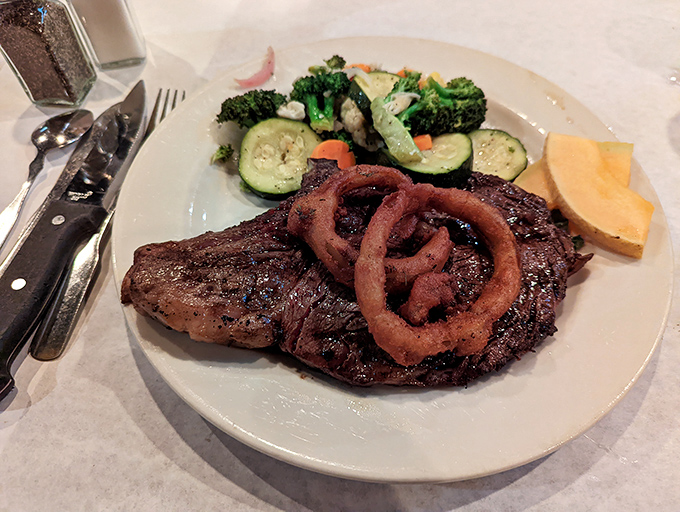 This isn't just a steak; it's a masterclass in the art of char. Those onion rings aren't a garnish&mdash;they're the crown jewels.