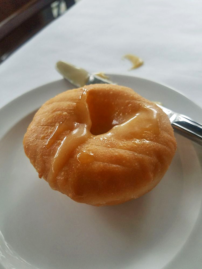 The legendary scone arrives like a golden pillow of buttery perfection, glistening with honey butter that melts on contact with both pastry and willpower.