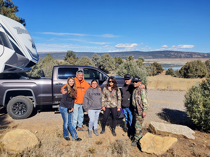 A group enjoying the fruits of outdoor adventure&mdash;that view behind them is the real celebrity here, quietly photobombing their memory.