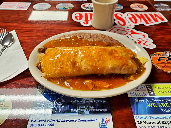 Behold the breakfast burrito in its natural habitat—smothered in cheese and chili, wearing its sauce like a superhero cape.