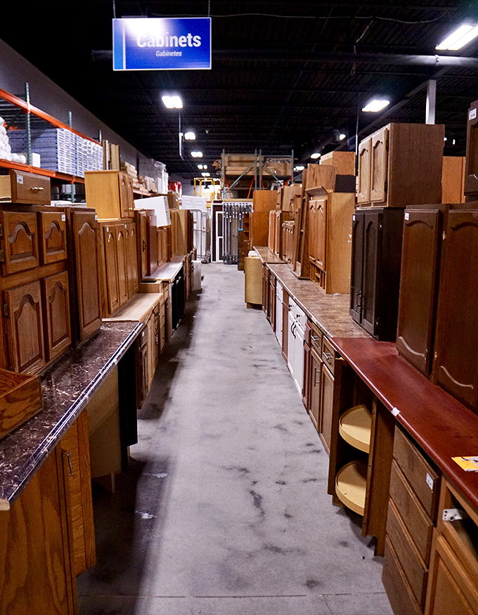 The cabinet aisle stretches like a wooden canyon of possibility. Somewhere in this forest of oak and cherry lies your kitchen's future.