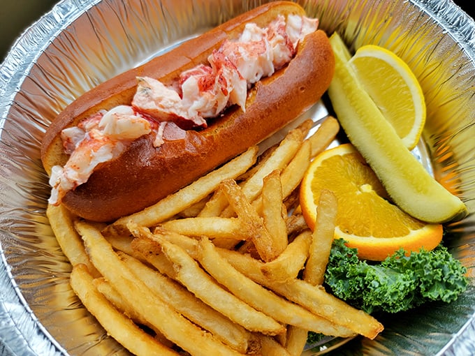 This isn't just a lobster roll; it's summer vacation on a buttered bun, accompanied by golden fries and the requisite pickle spear for good measure.