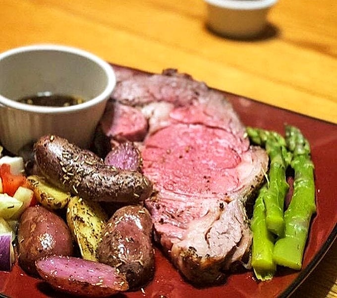 The prime rib arrives like a carnivore's dream &ndash; perfectly pink, surrounded by colorful vegetables, and accompanied by a jus that deserves its own fan club.
