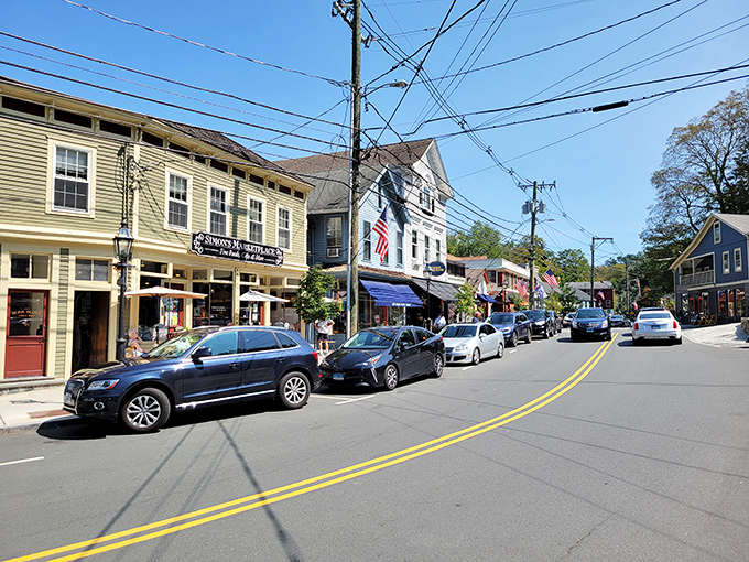 Charming Connecticut main street with colorful historic buildings, American flags, and parked cars along a sunny downtown strip creates the perfect small-town balance.